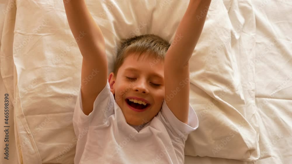 Morning awakening Caucasian boy 6-9 years old in bed. Positive boy ...