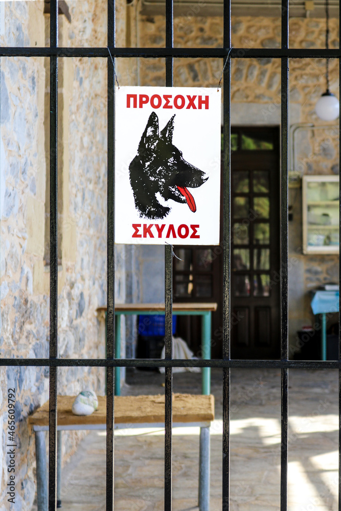 Beware of dog sign in Greek language on metal fence to outdoor rock ...