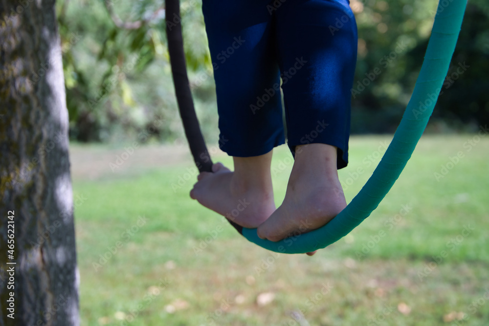 Detail of a woman's feet on an aero hoop hanging from a tree branch in ...