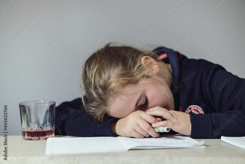 Exhausted school girl sleeping at desk while doing lots of homework ...