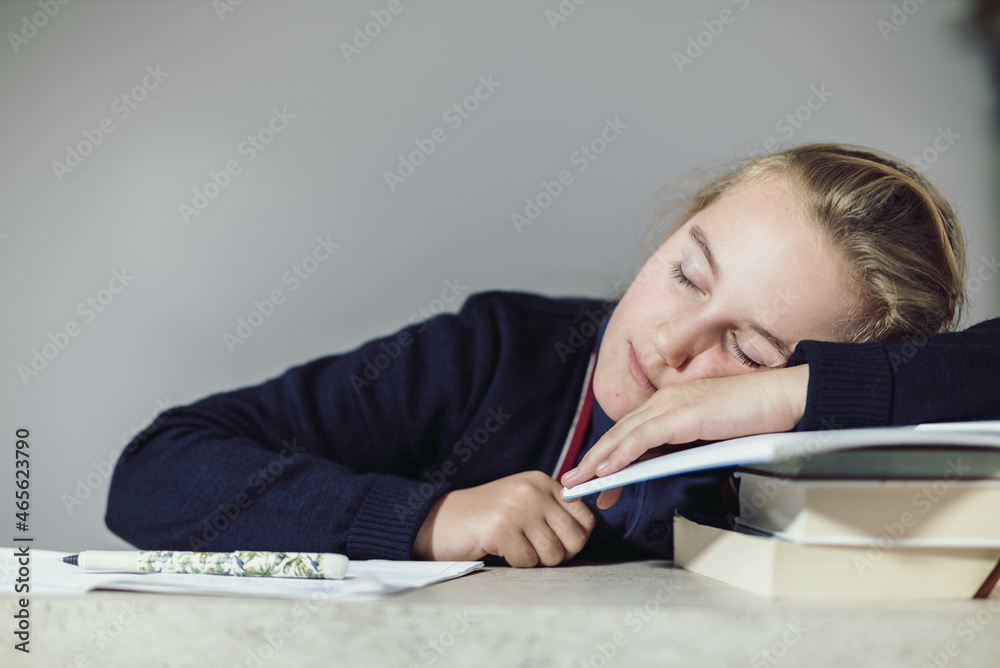 Exhausted school girl sleeping at desk while doing lots of homework ...