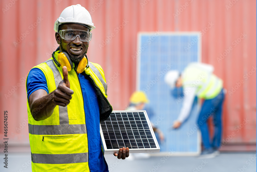 Factory engineer African man standing confidence and holding solar cell panel for renewable energy engineering. Worker staffs checking solar cell panel for renewable energy construction. Stock Adobe S...