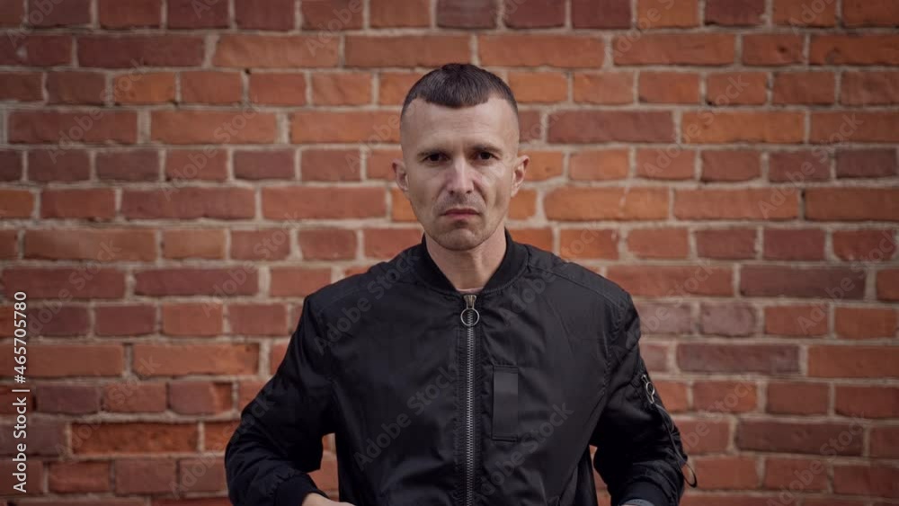 An angry caucasian male guard with a short haircut in a black jacket ...