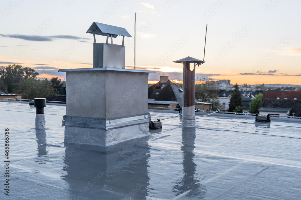 Flat roof covered with bitumen membrane and silver lacquer with chimney ...