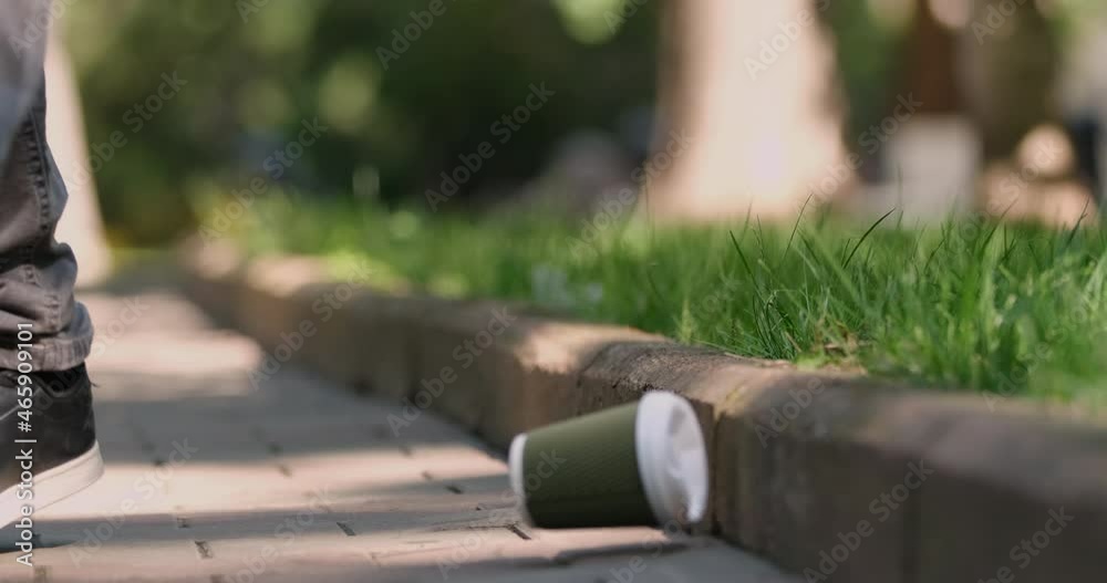 A passing man on the road puts a glass without coffee on the side of ...