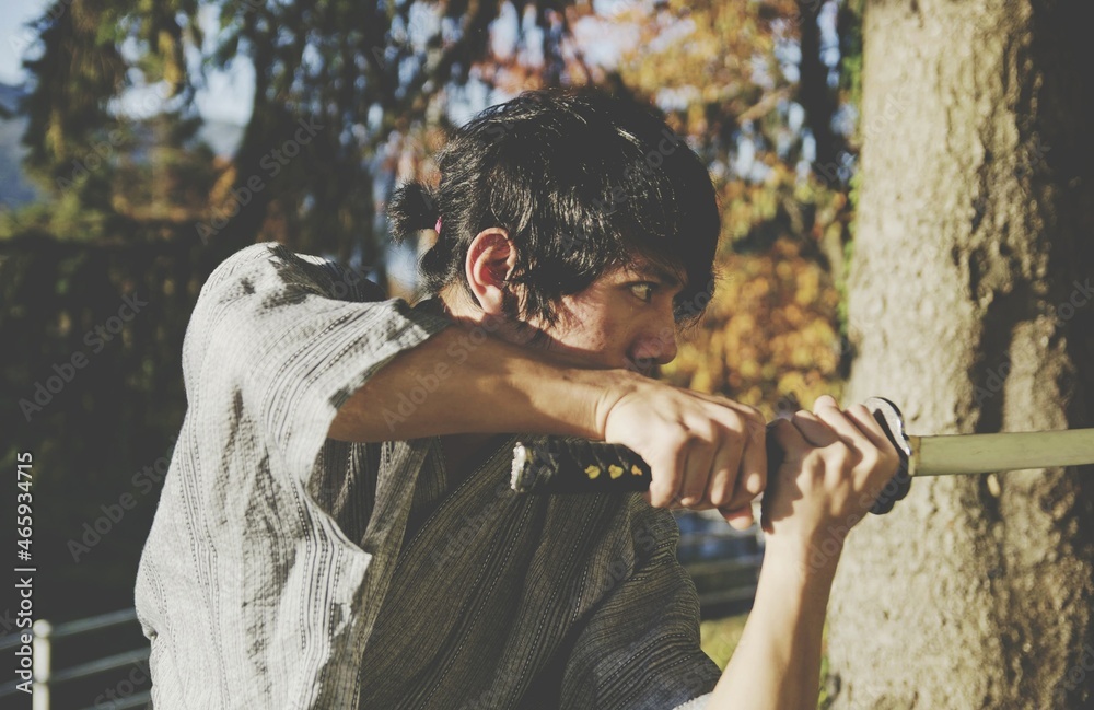 Portrait Of Young Man Standing Against Tree Stock Photo | Adobe Stock