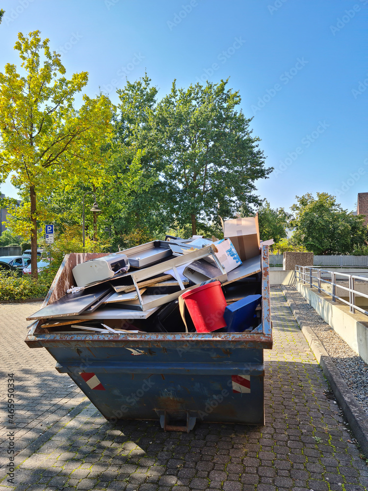 Foto de A full rusty metal skip container with rubbish stands on the ...