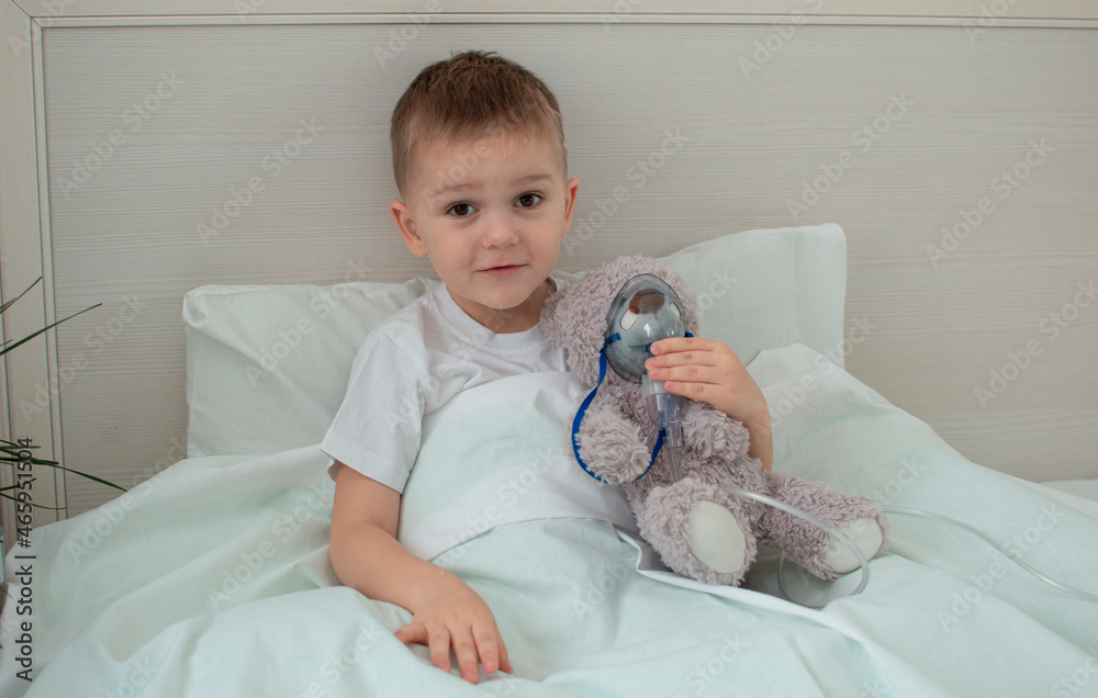 Sick child is sick at home, lying in bed with teddy bear. Does the ...
