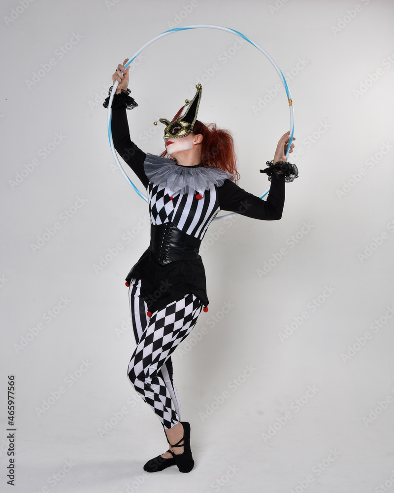 Full length portrait of red haired girl wearing a black and white clown ...