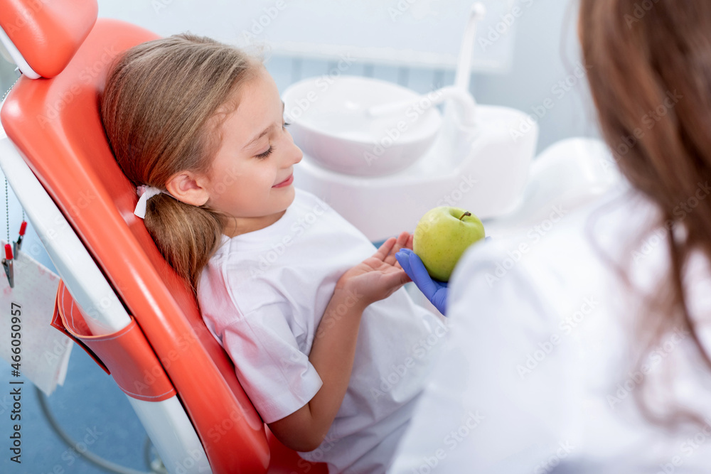 child girl in white clothes at reception at a pediatric dentist smiles ...
