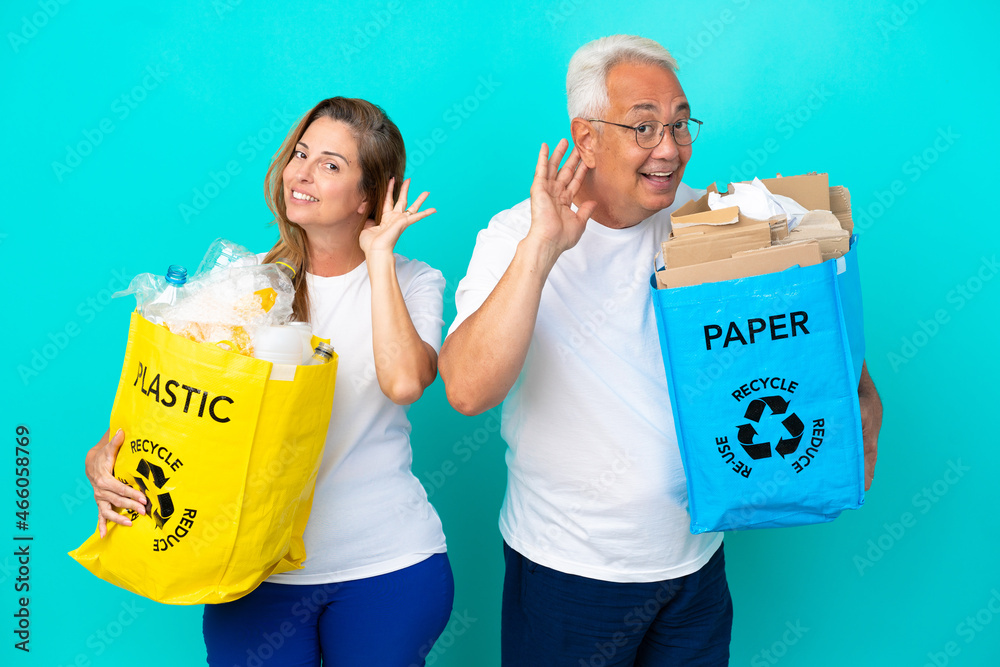 Middle age couple holding a recycling bags full of paper and plastic ...