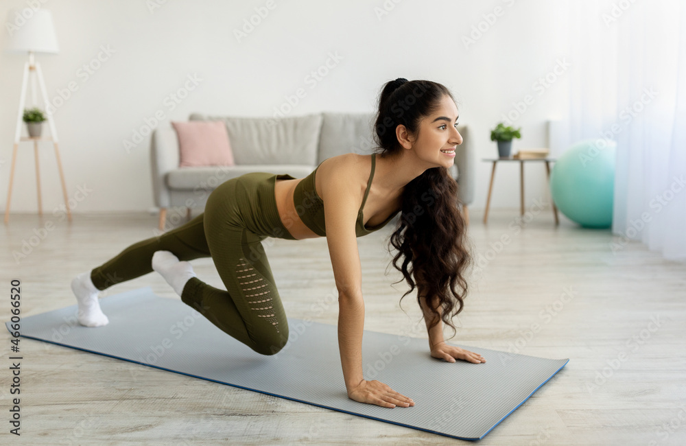 Beautiful young Indian woman doing strength exercises, training her abs ...
