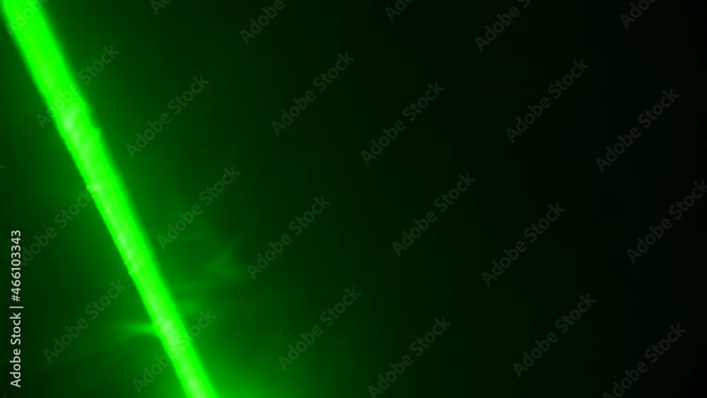 Colorful green neon laser lights on black studio background spinning in ...