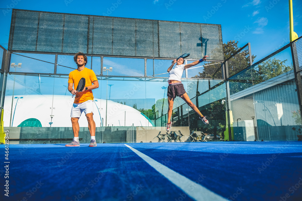 Mixed padel match in a blue grass padel court - Beautiful girl and ...