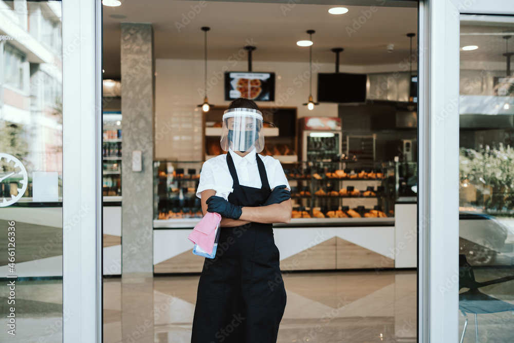 Beautiful woman with face shield and protective mask working bakery or ...