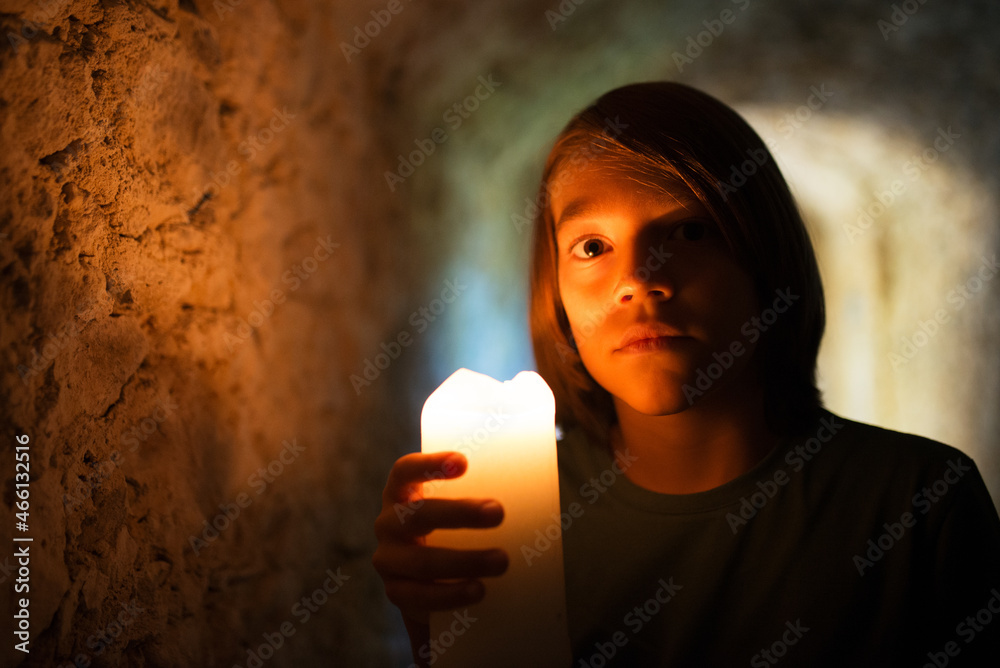 Bold little boy exploring old castle. Dark haired boy holding candle in ...
