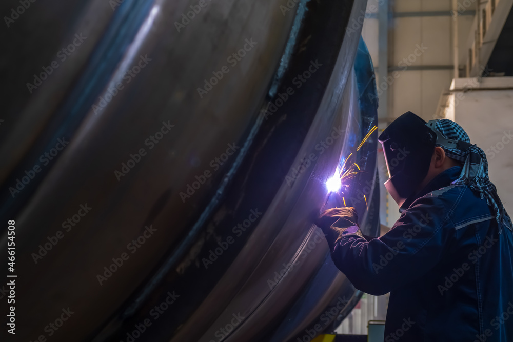 MMA welding. A welder welds large diameter pipes with manual electric ...