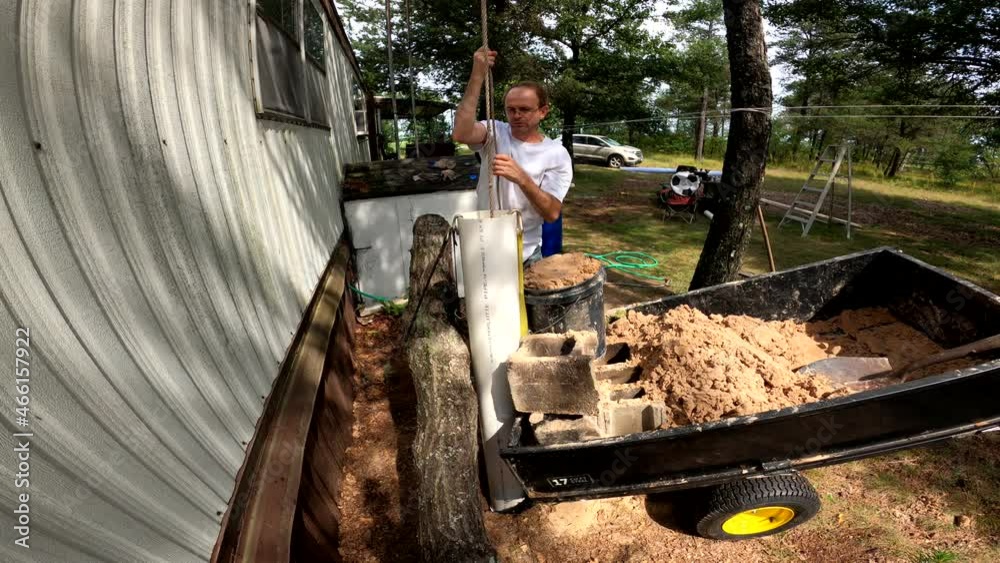 Man pulling rope with metal pipe at the end excavating sand collected ...