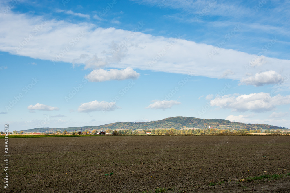Krajobraz. Na pierwszym planie zaorane pole - brązowa ziemia, w tle ...