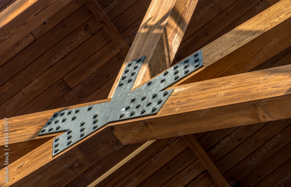 Metal steel connector secures three wooden beams as part of a roof ...