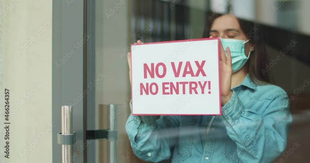 Caucasian business owner female wearing face mask attaching sign on the ...