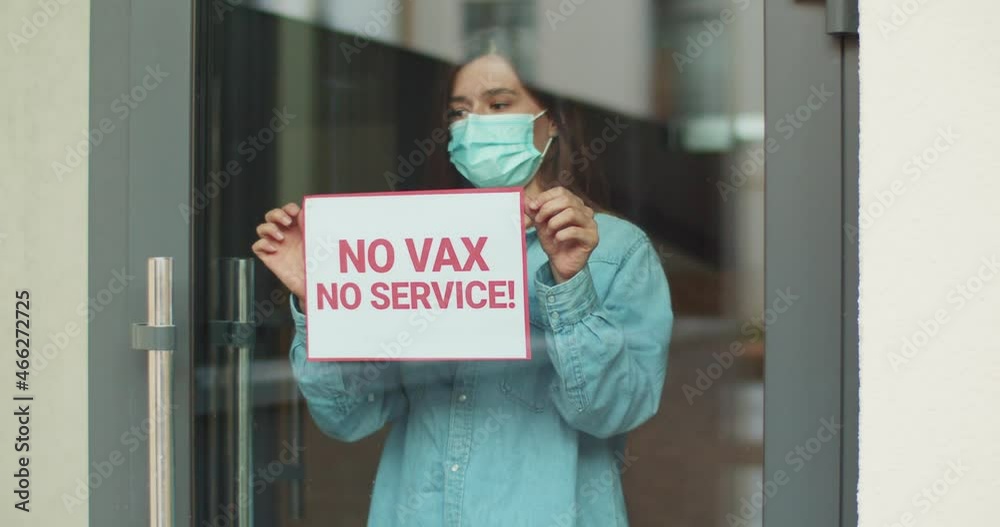 Woman wearing face mask attaching sign on the glass in pandemic time ...