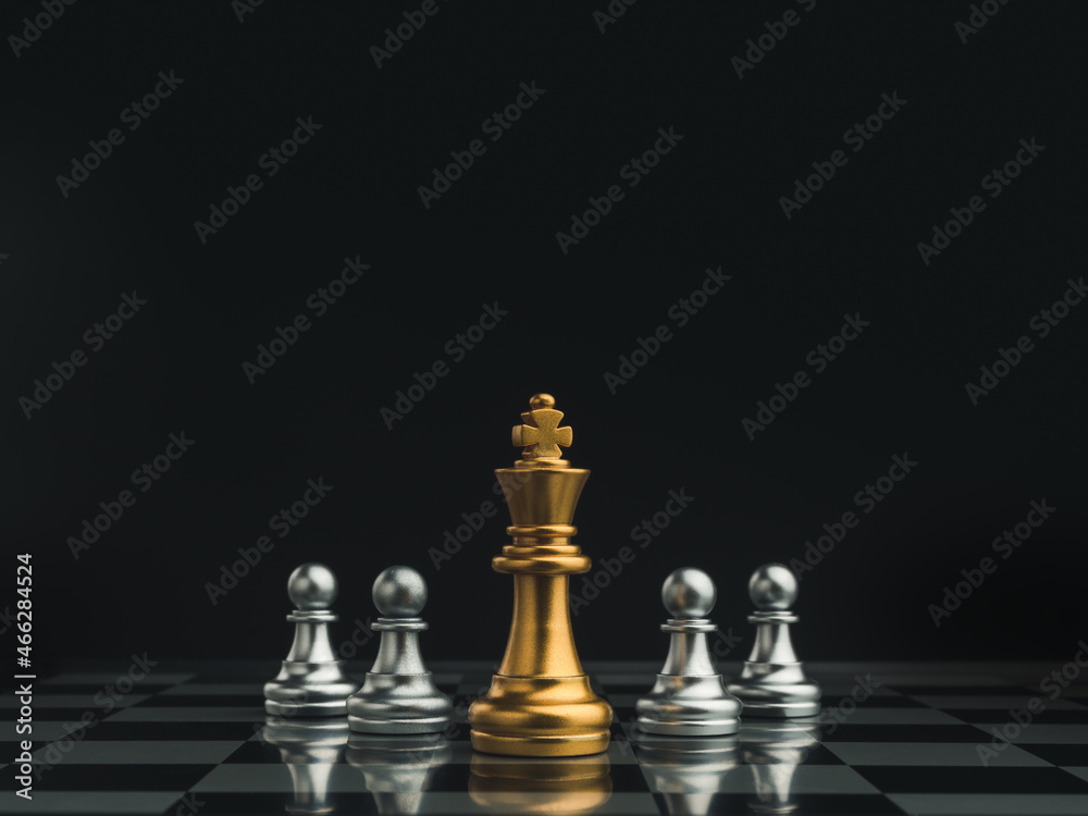 Golden queen chess piece standing in the center of little silver pawn ...