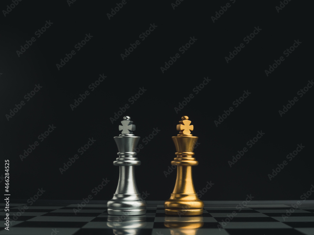 A golden queen chess piece and a silver queen chess piece are standing ...