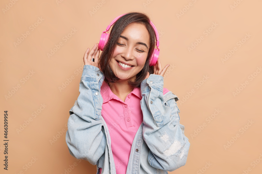Positive good looking teenage girl enjoys music catches every bit of ...