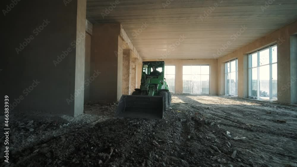 The tractor works in an unfinished building. Internal construction work ...