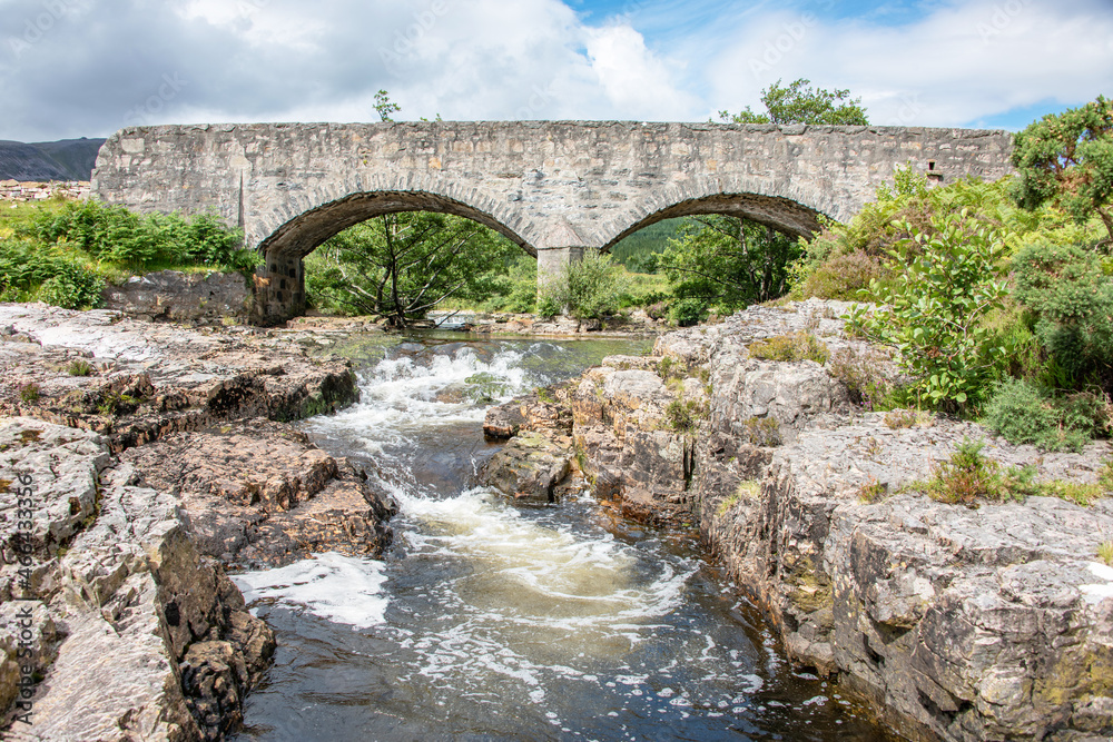 River flowing under a double arched bridge in the Highlands of Scotland ...