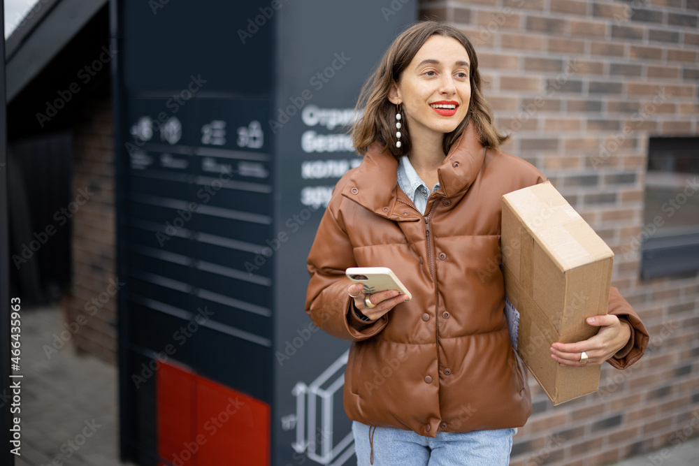 Young caucasian woman with parcel near automatic post terminal. Smiling ...