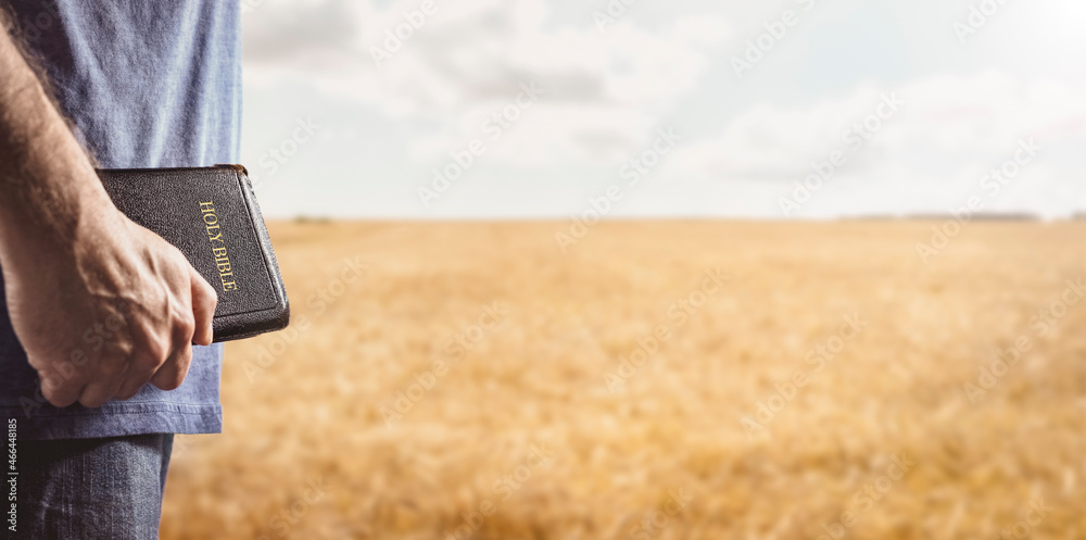 Christian man holding the Holy Bible in a field background Stock Photo ...