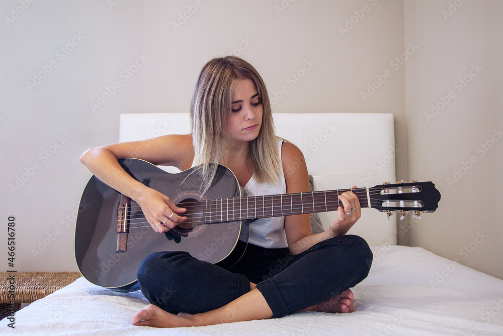 Chica tocando la guitarra en su habitación. Mujer mirando su guitarra española mientras toca en ...