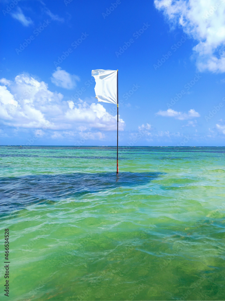 White flag flies in turquoise waters of the Caribbean Sea and tropical ...