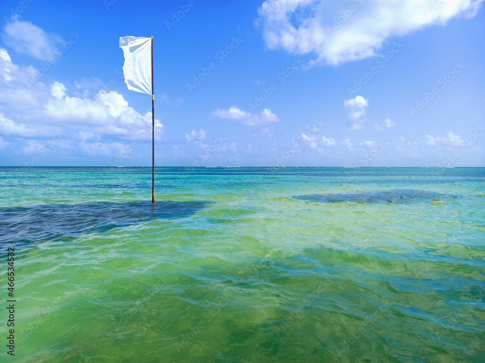 White flag flies in turquoise waters of the Caribbean Sea and tropical ...