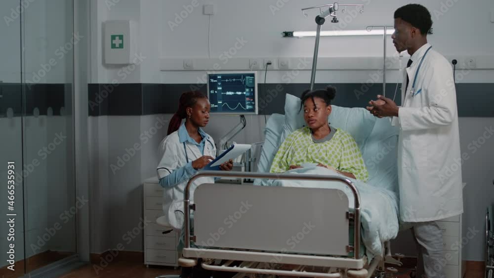 Medical team talking to sick woman in hospital ward bed. Man and woman ...