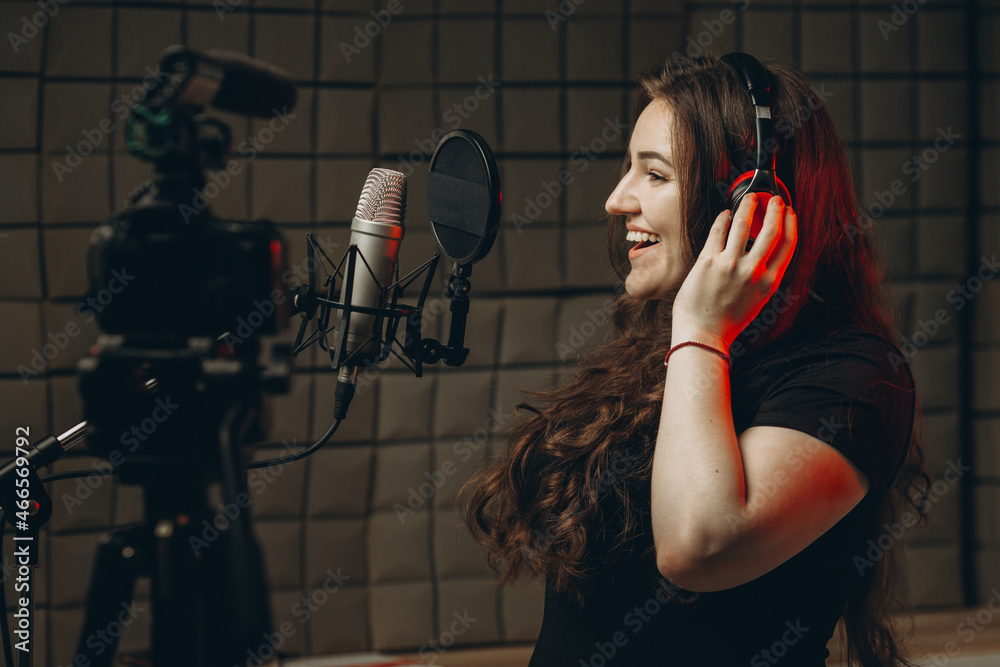 Young girl with microphone and headphones in recording studio ...