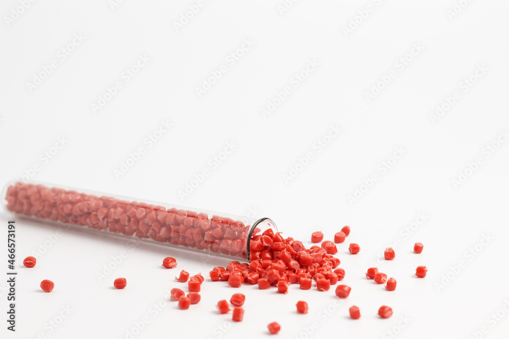 Red granules of polypropylene, polyamide in a measuring beaker and a ...