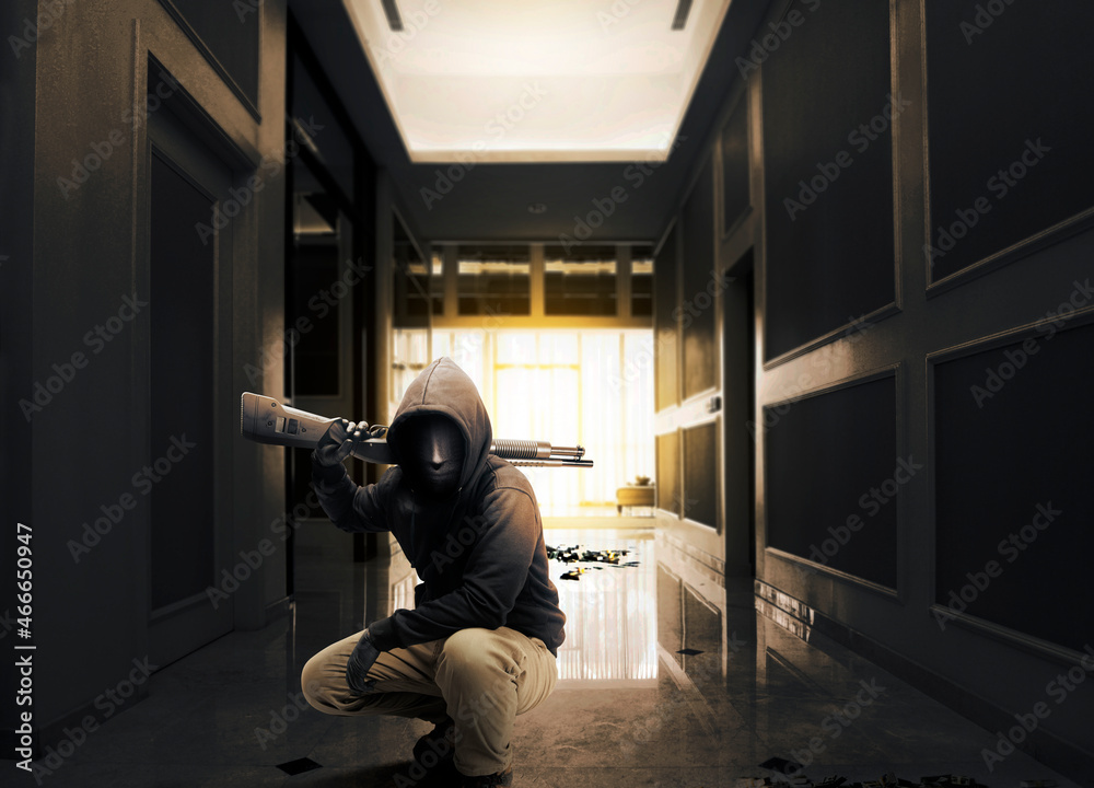 Criminal man in a hidden mask sitting and holding the shotgun while ...