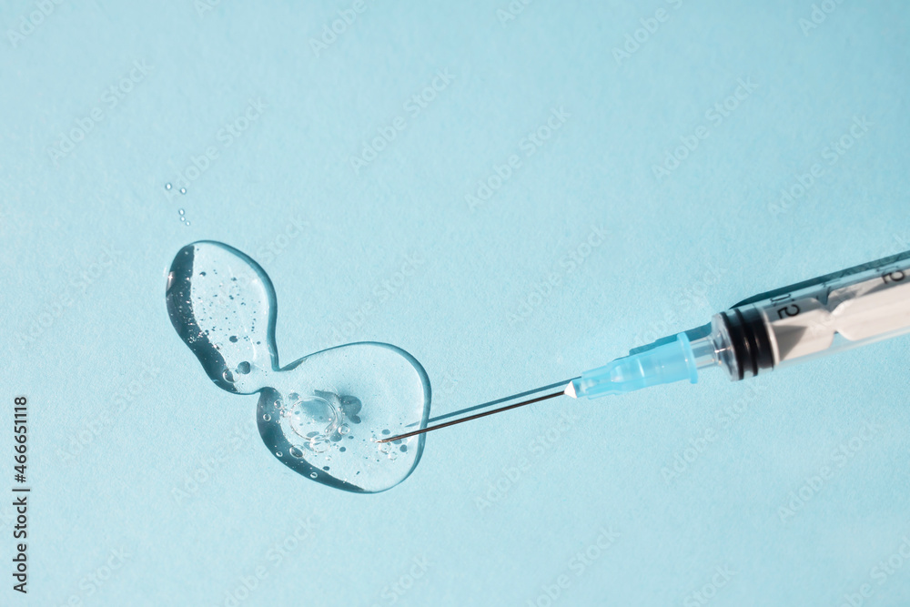 Disposable syringe with a transparent gel-like liquid on a blue ...