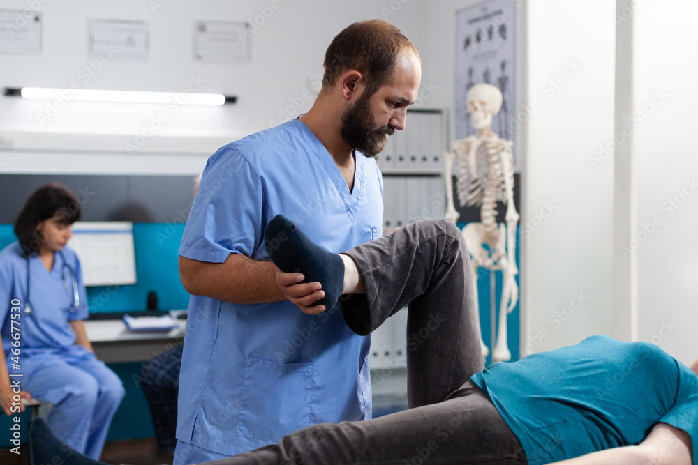 Chiropractic physician helping aged woman with leg muscle pain in ...