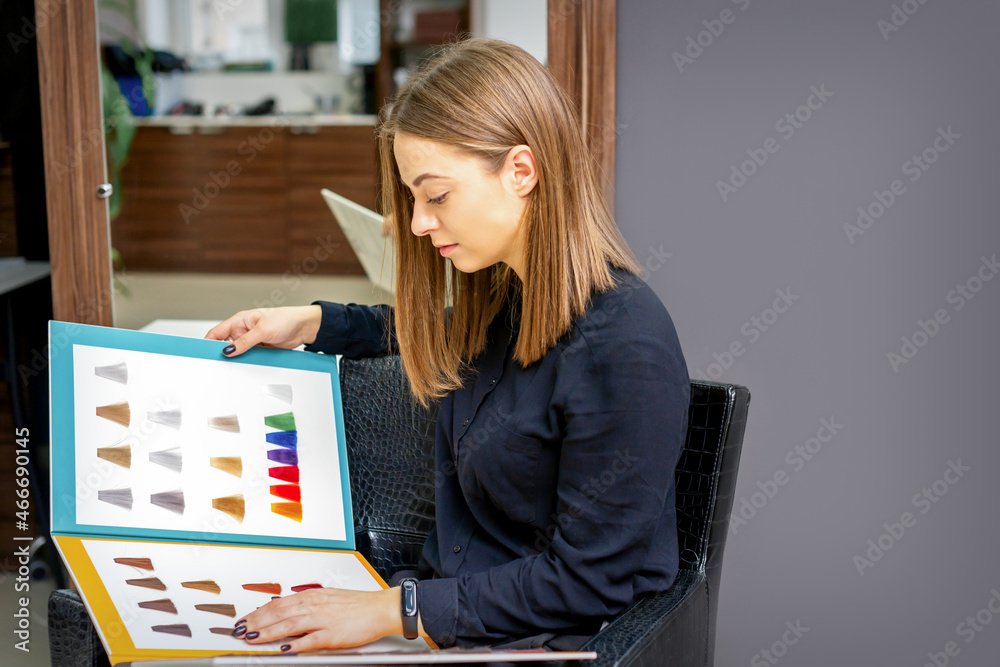 Young caucasian woman choosing a color from the hair color chart in a ...