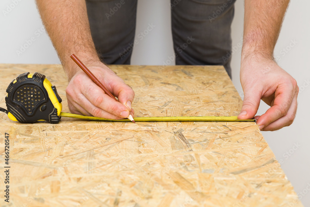 Young adult man hands measuring osb board with measure tape and marking ...