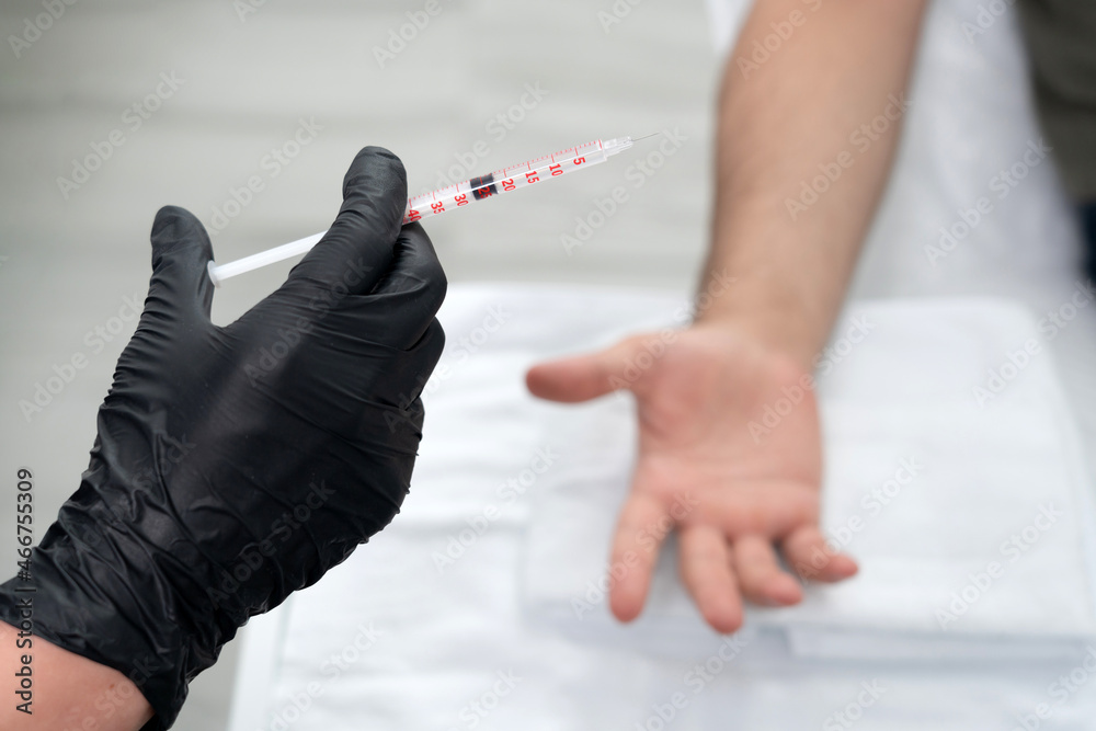 doctor makes a shot of botulinum toxin in the hand of a male palm ...