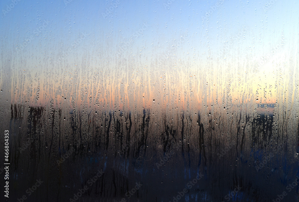 Sunrise. Sunset. Through a fogged window with dripping water drops, a ...