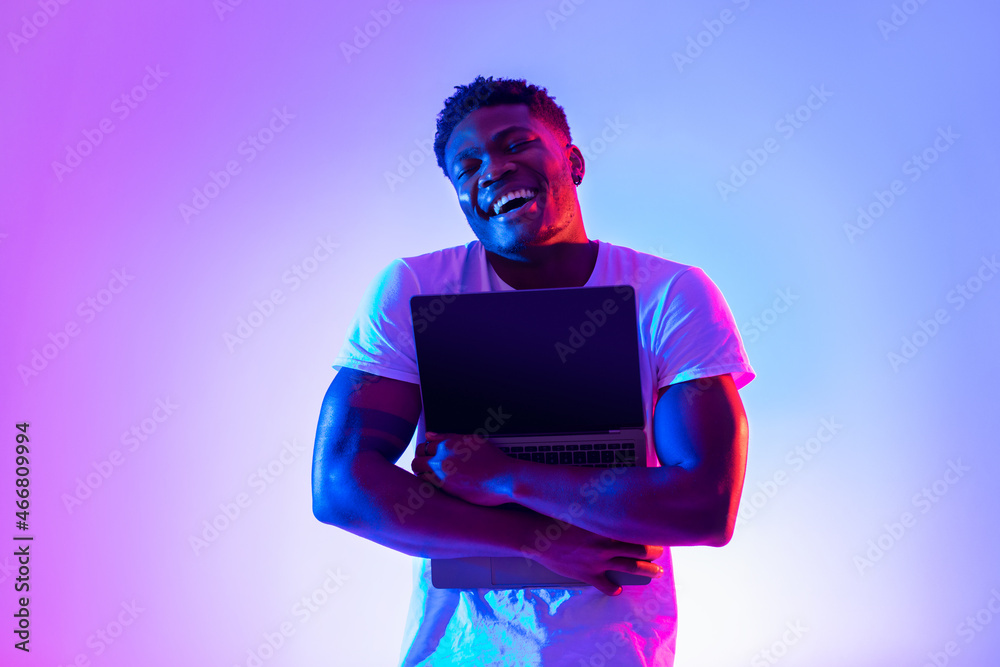 Technology lover concept. Happy black man hugging laptop with blank ...