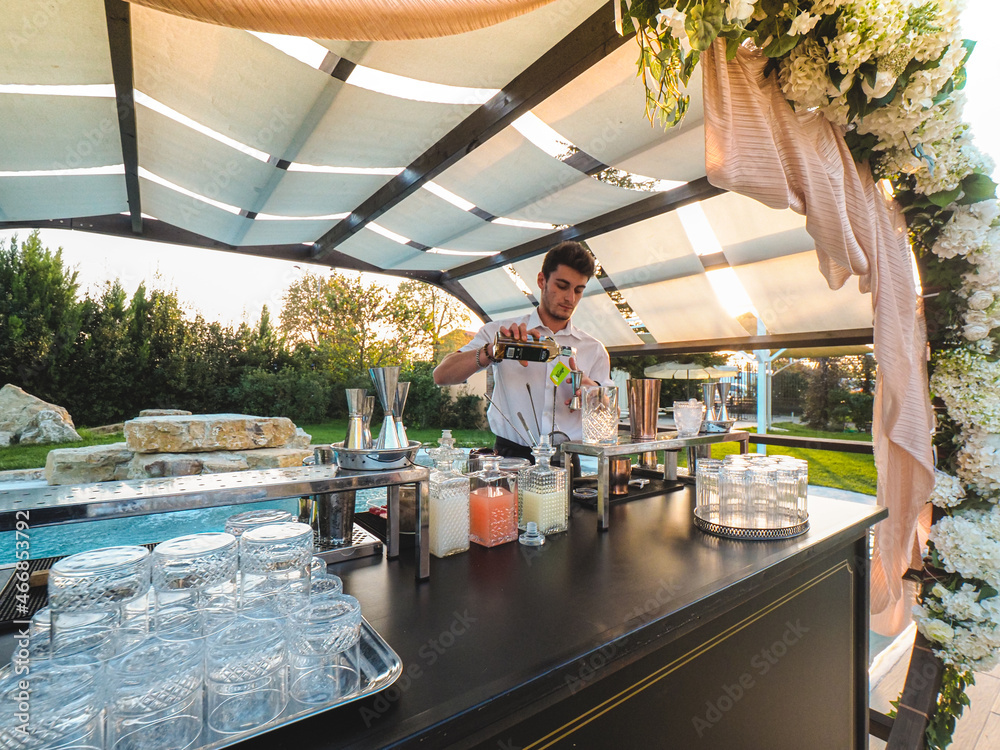 young caucasian bartender at work in a cocktail station outdoors in a ...