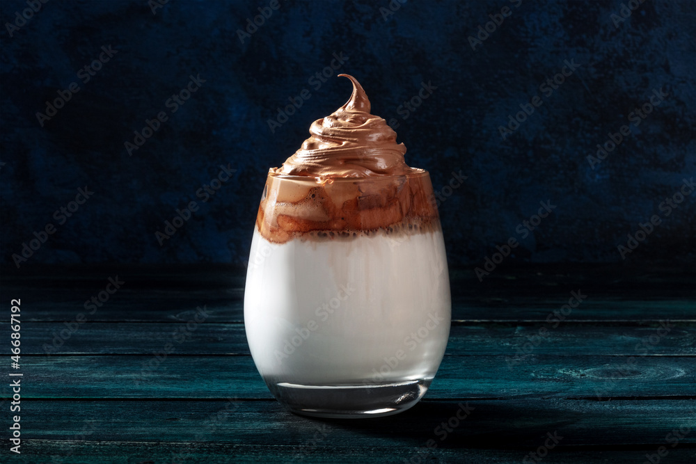 Dalgona cold coffee, side view on a dark background. Sweet Korean drink ...