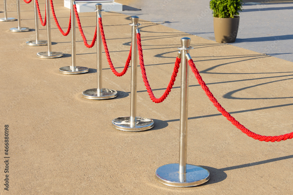 Portable fencing shiny metallic barrier outside. Red carpet safety rope ...